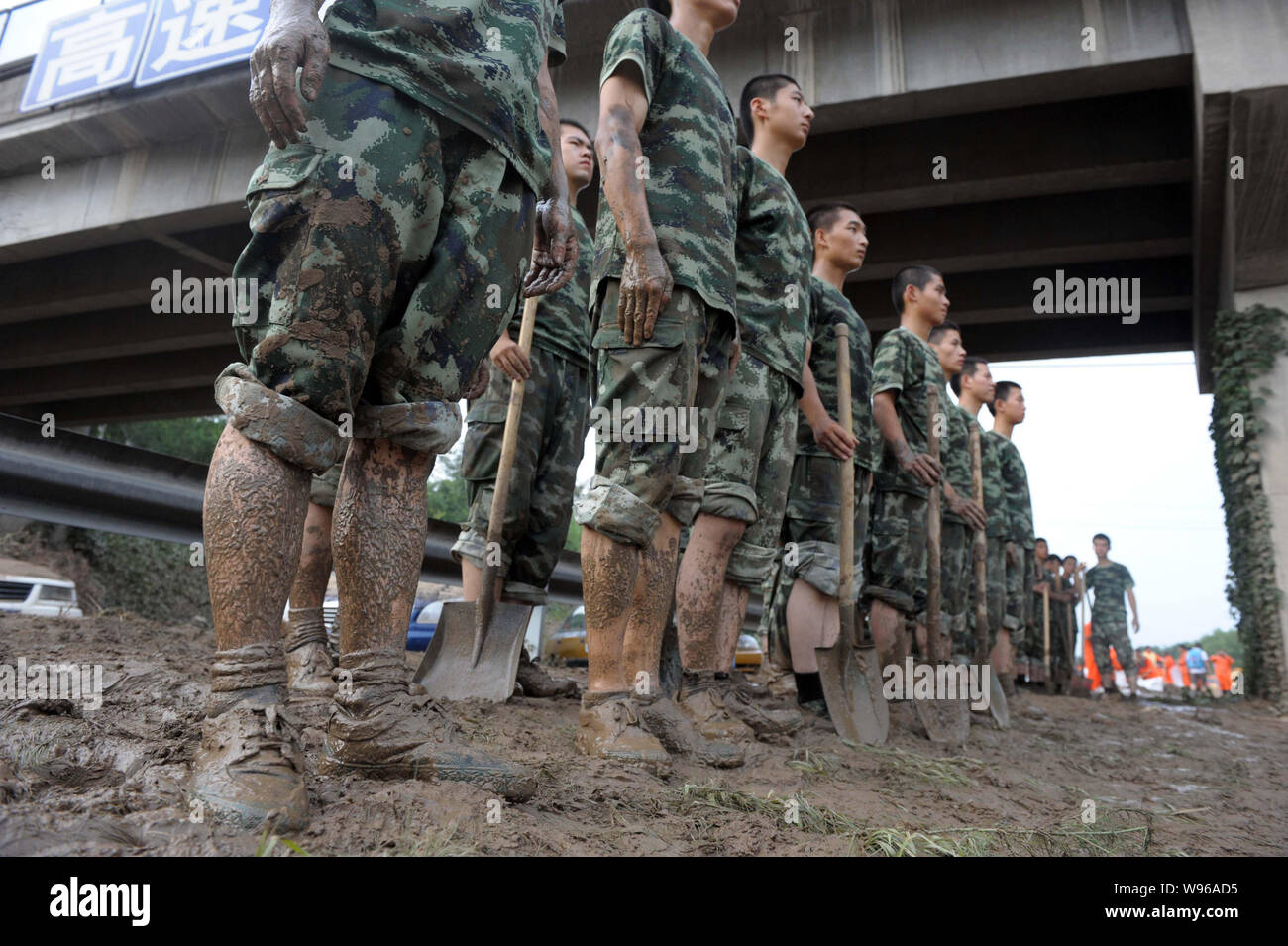 Chinese soldiers stand in line when clearing away mud on the flooded ...