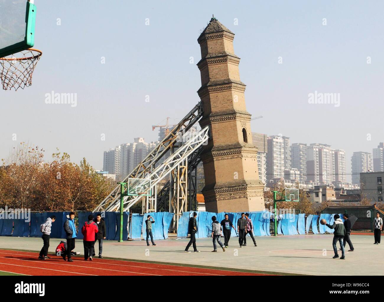 Chinese students play basketball on the playground next to the leaning ...