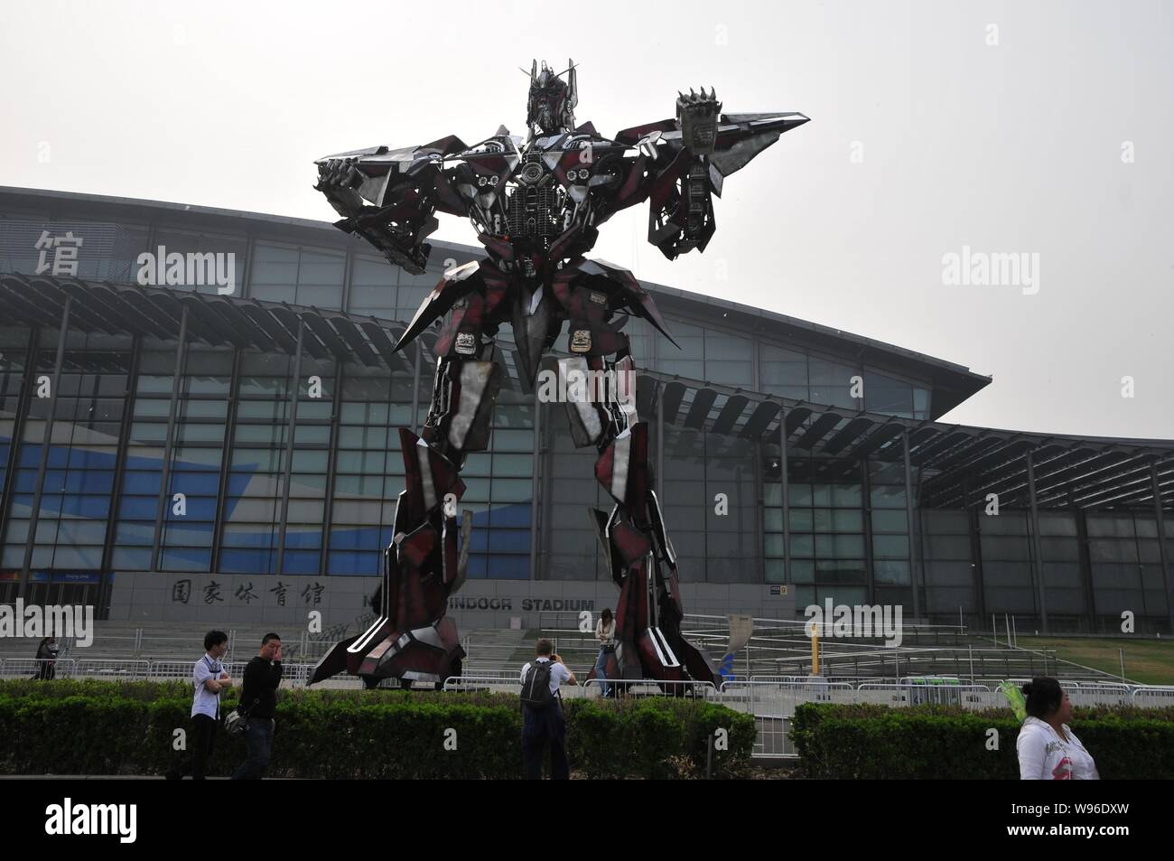 Pedestrians walk past a giant transformer model at Beijing Olympic Park ...