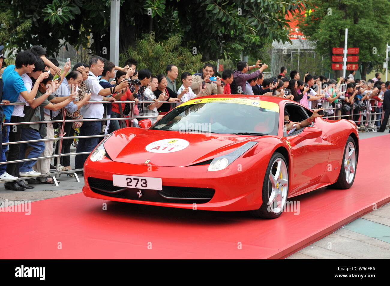 People look at and take photos of Ferrari sports cars arriving on the ...
