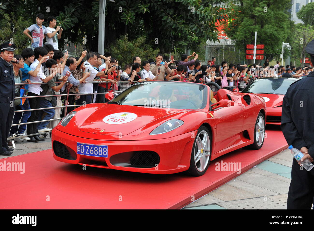 People look at and take photos of Ferrari sports cars arriving on the ...