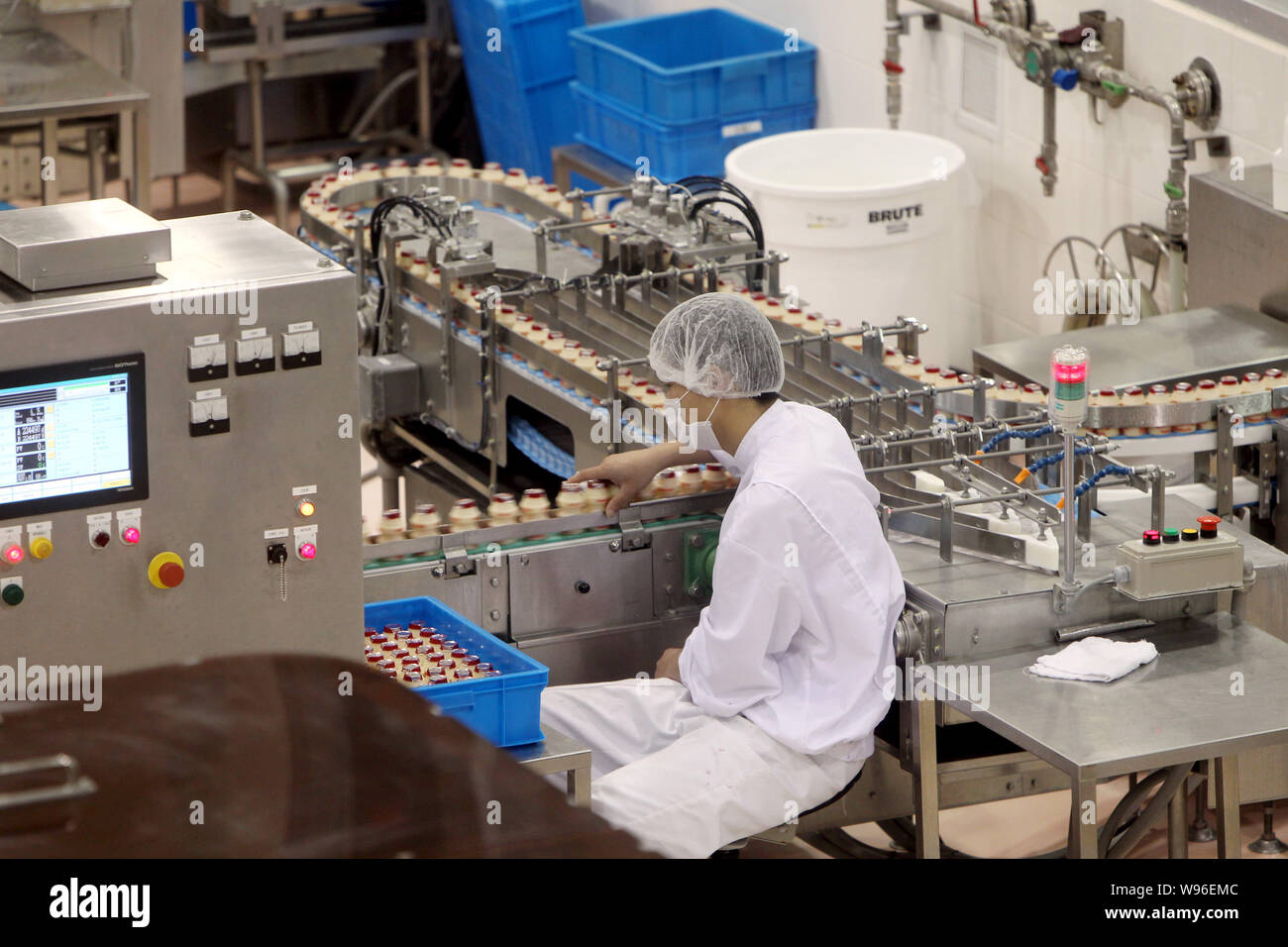 A factory worker watches bottles of Yakult fermented milk drink passing ...