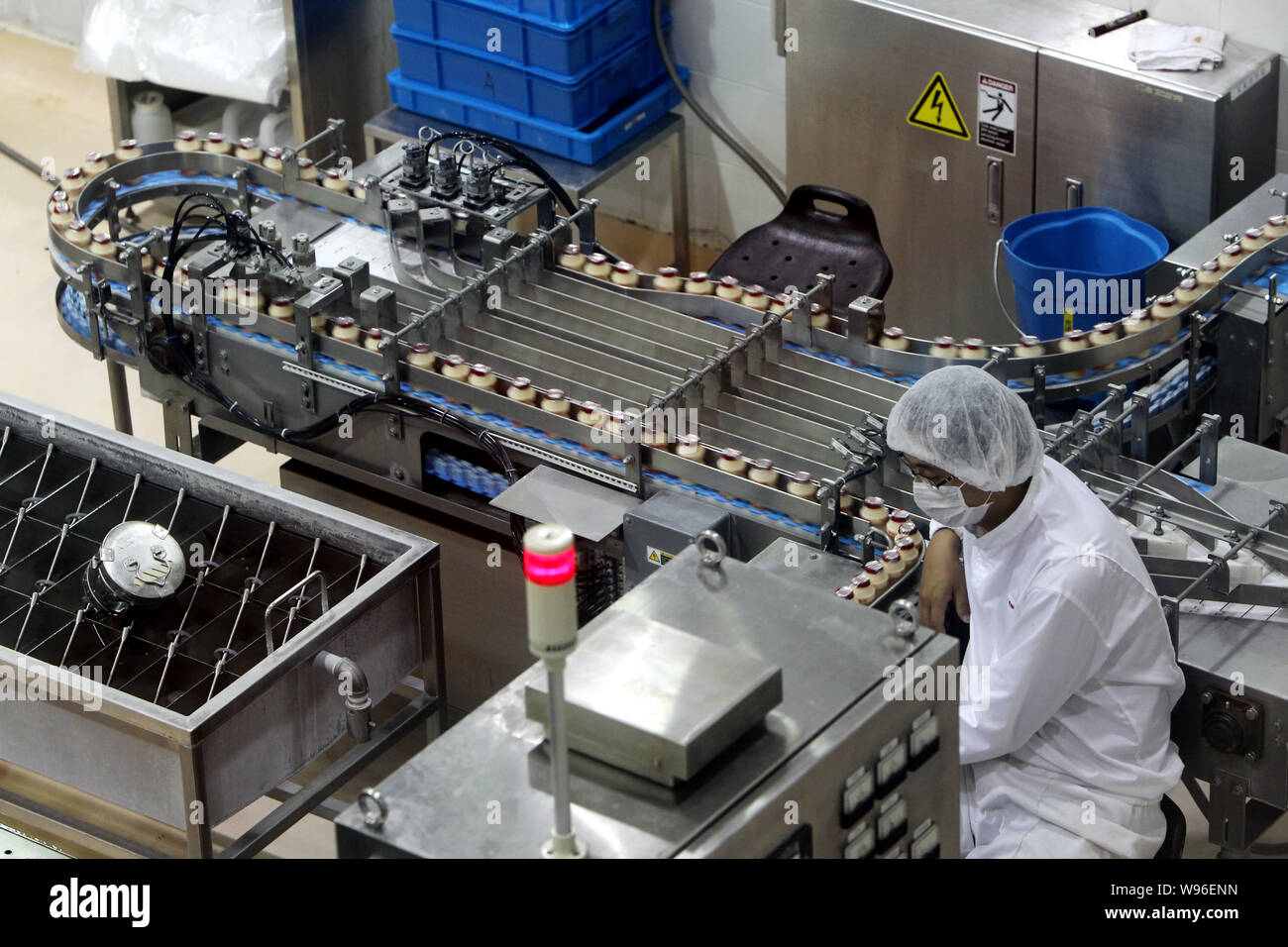 A factory worker watches bottles of Yakult fermented milk drink passing ...