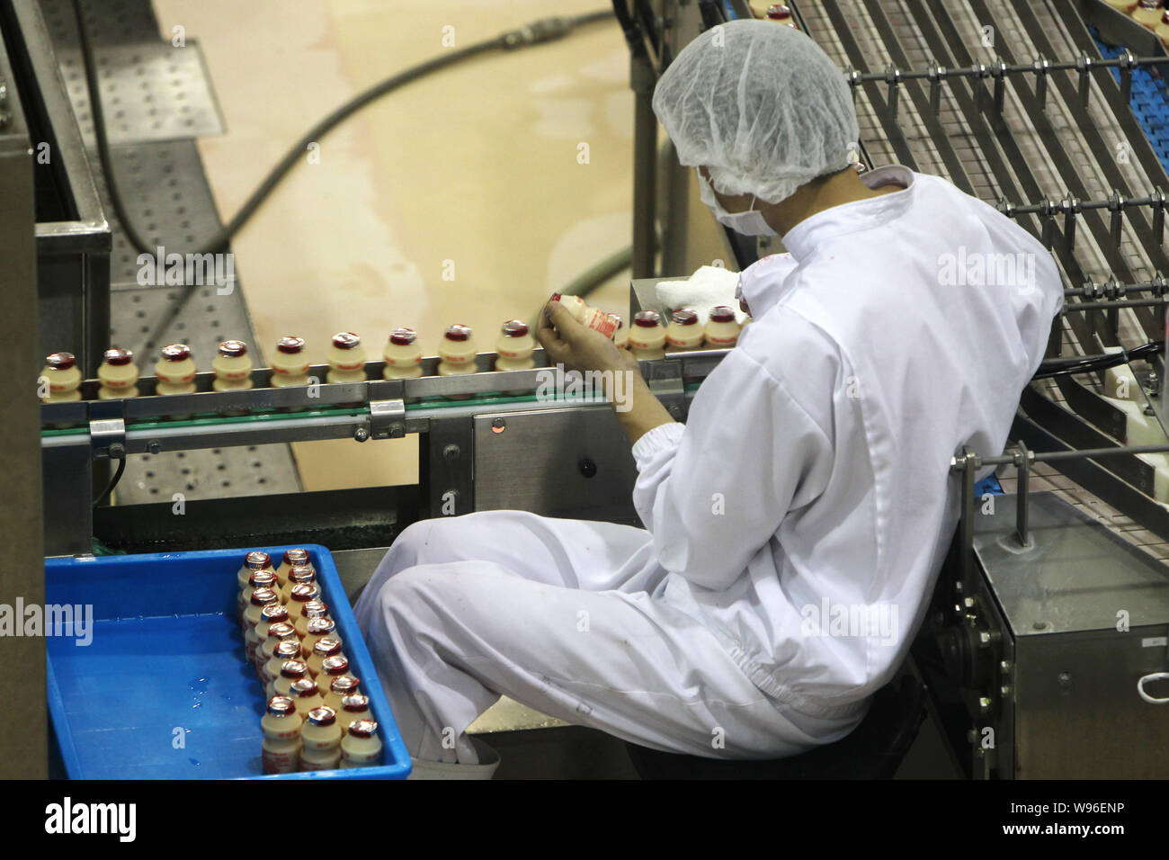 A factory worker watches bottles of Yakult fermented milk drink passing ...