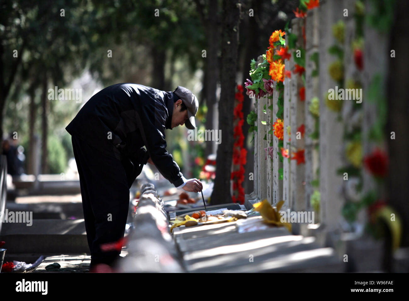 A man paints his family grave at the Babaoshan Cemetery ahead of the ...
