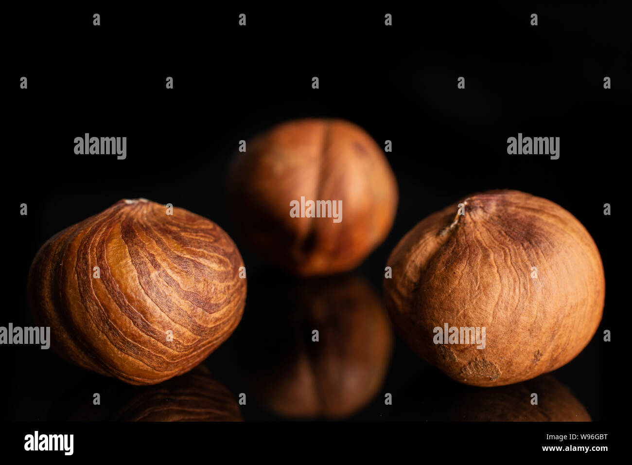 Group of three whole ripe brown hazelnut arranged symmetrically in ...