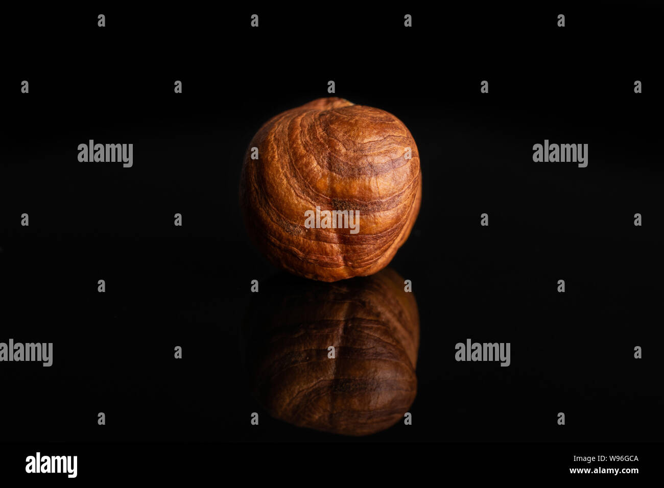 One whole ripe brown hazelnut in closeup isolated on black glass Stock ...