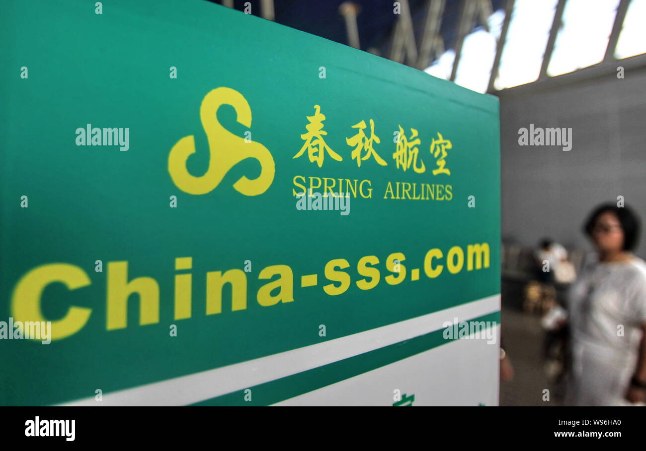 A passenger walks past the logo of Spring Airlines at Shanghai Pudong ...