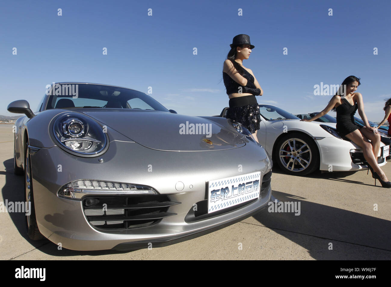 Chinese models pose with Porsche roadsters during a test drive at the ...
