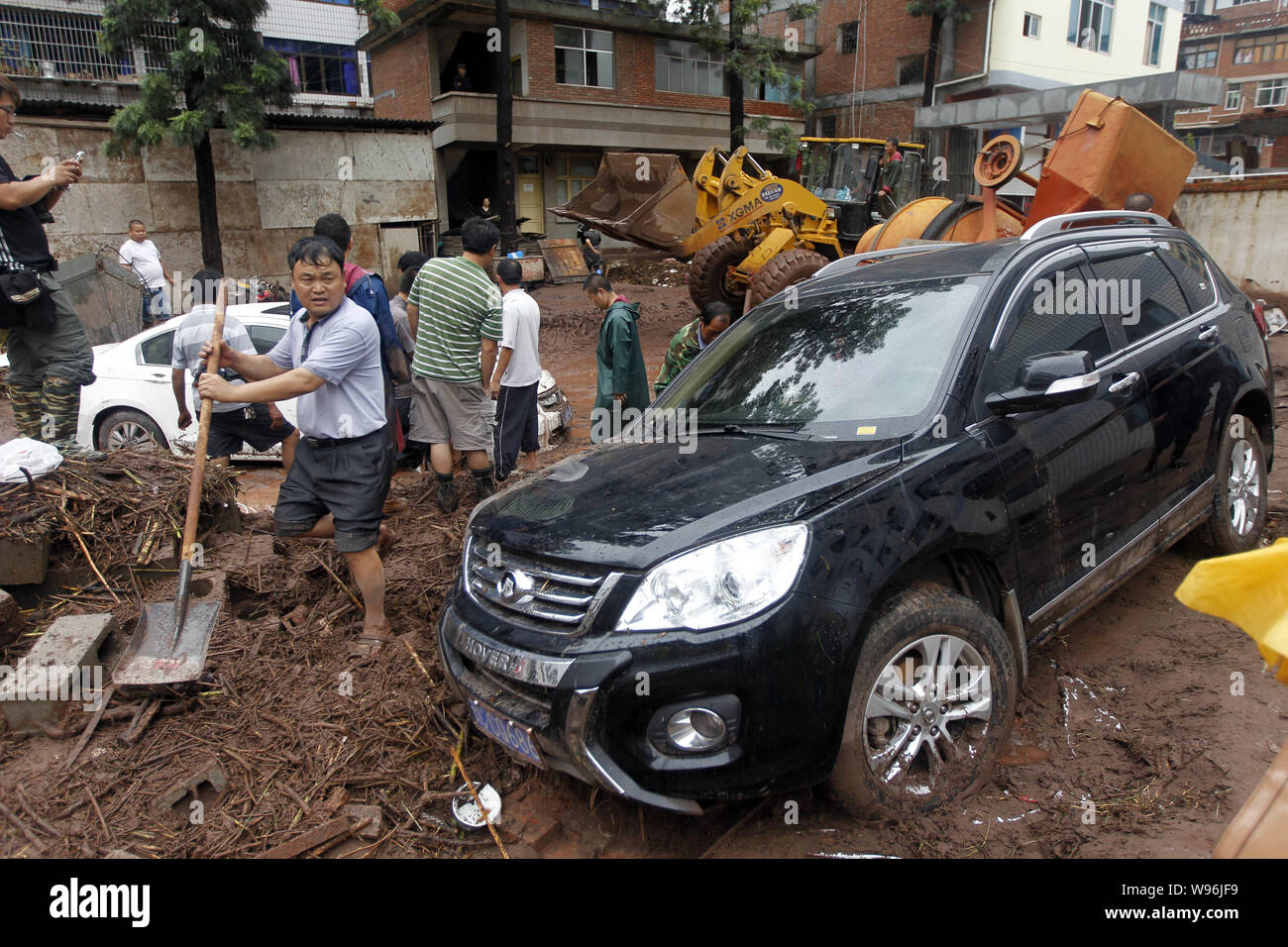Rescuers try to remove a car out of mud on a muddy street hit by a ...