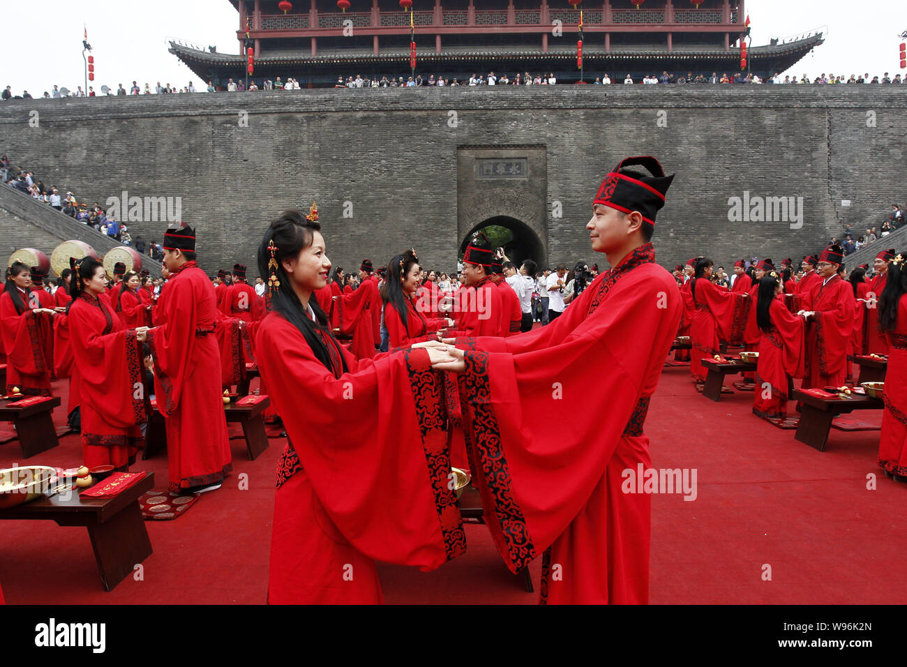 Couples of newlyweds dressed in traditional Han costumes hold hands as ...