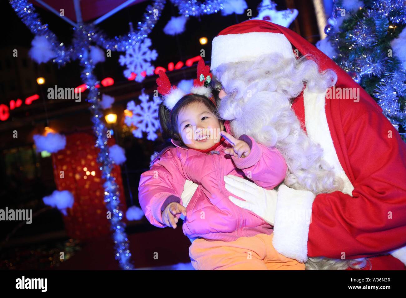 A young Chinese girl poses with a Santa Claus from Finland during a ...