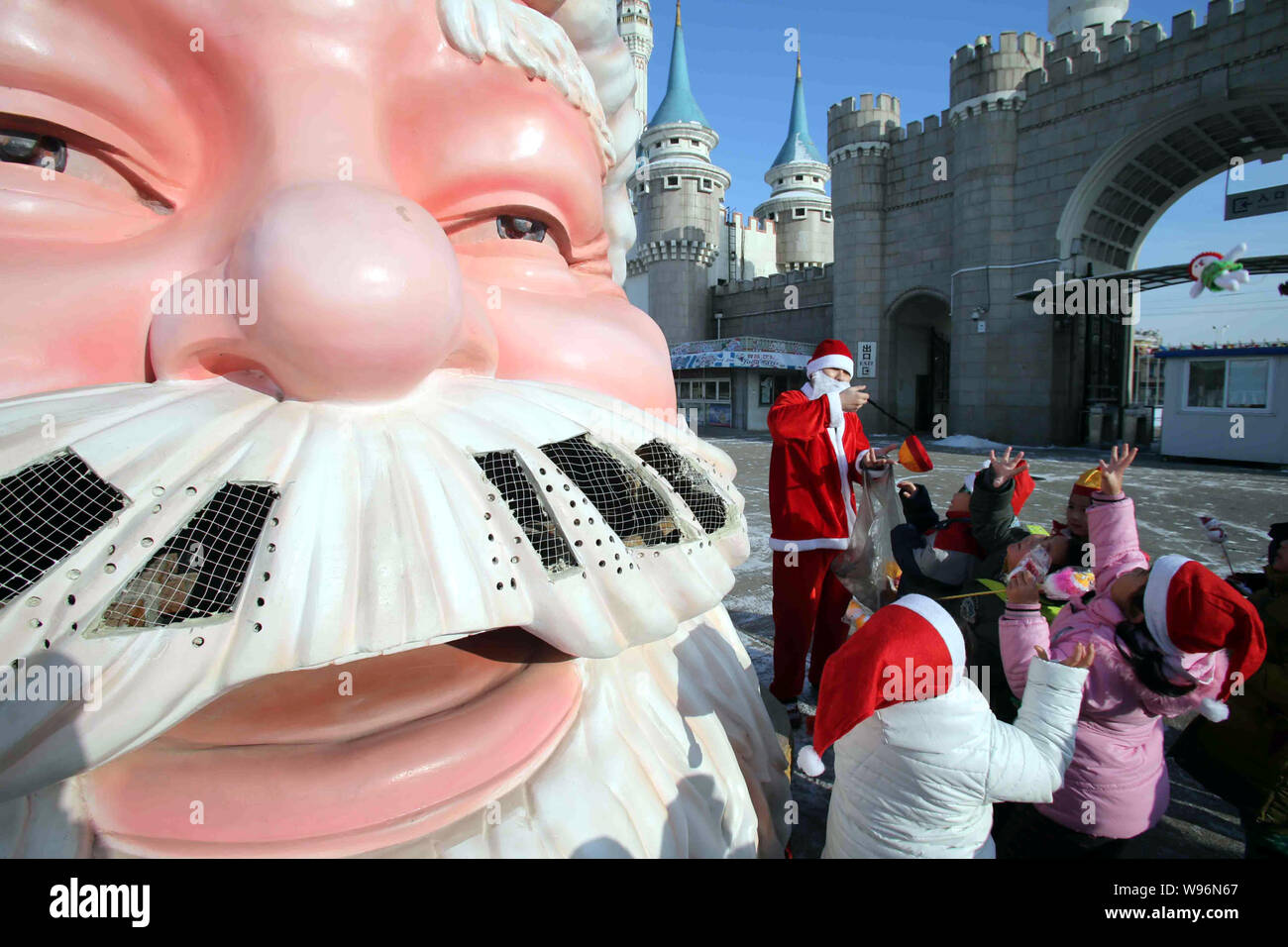 A young Chinese man dressed in a Santa Claus costume distributes gifts ...