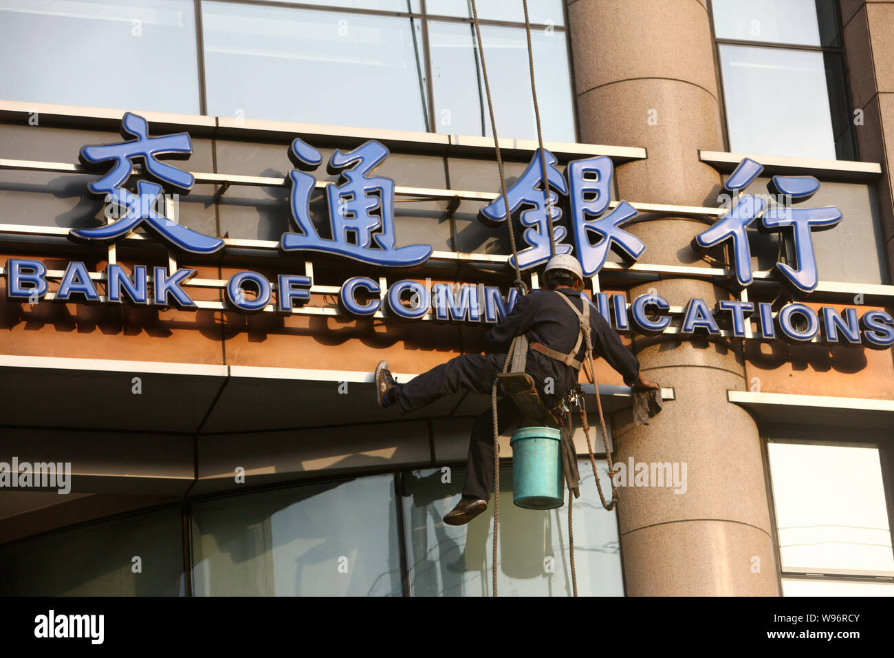 --FILE--A Chinese worker cleans the facade of a branch of Bank of ...