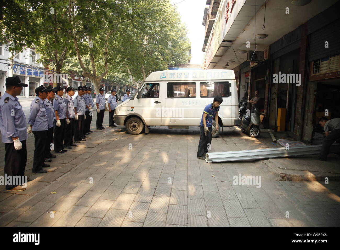 A line of urban management officers, known as chengguan, stare in ...