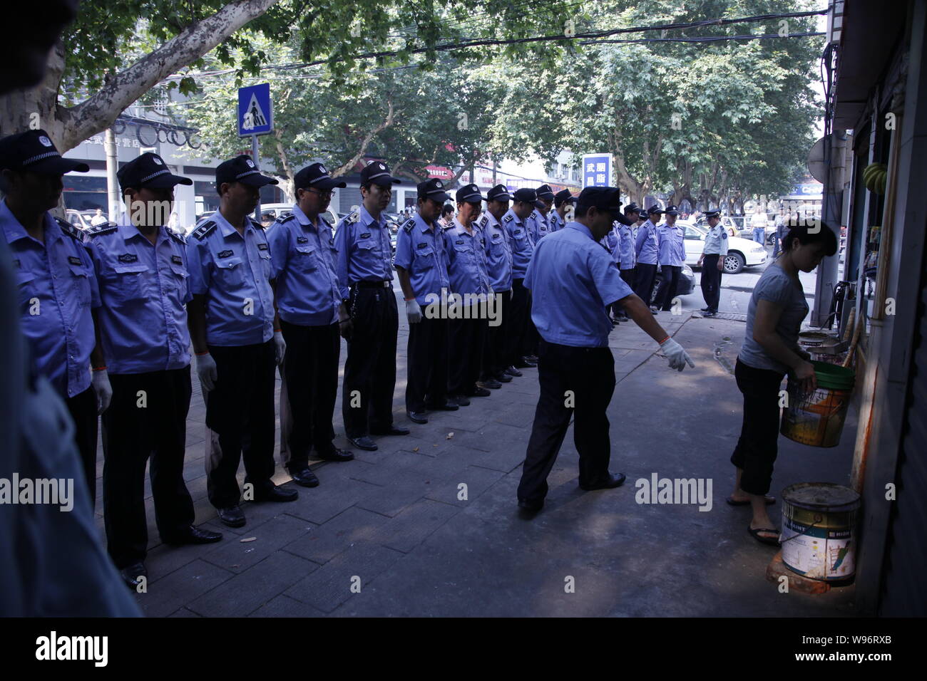 A line of urban management officers, known as chengguan, stare in ...