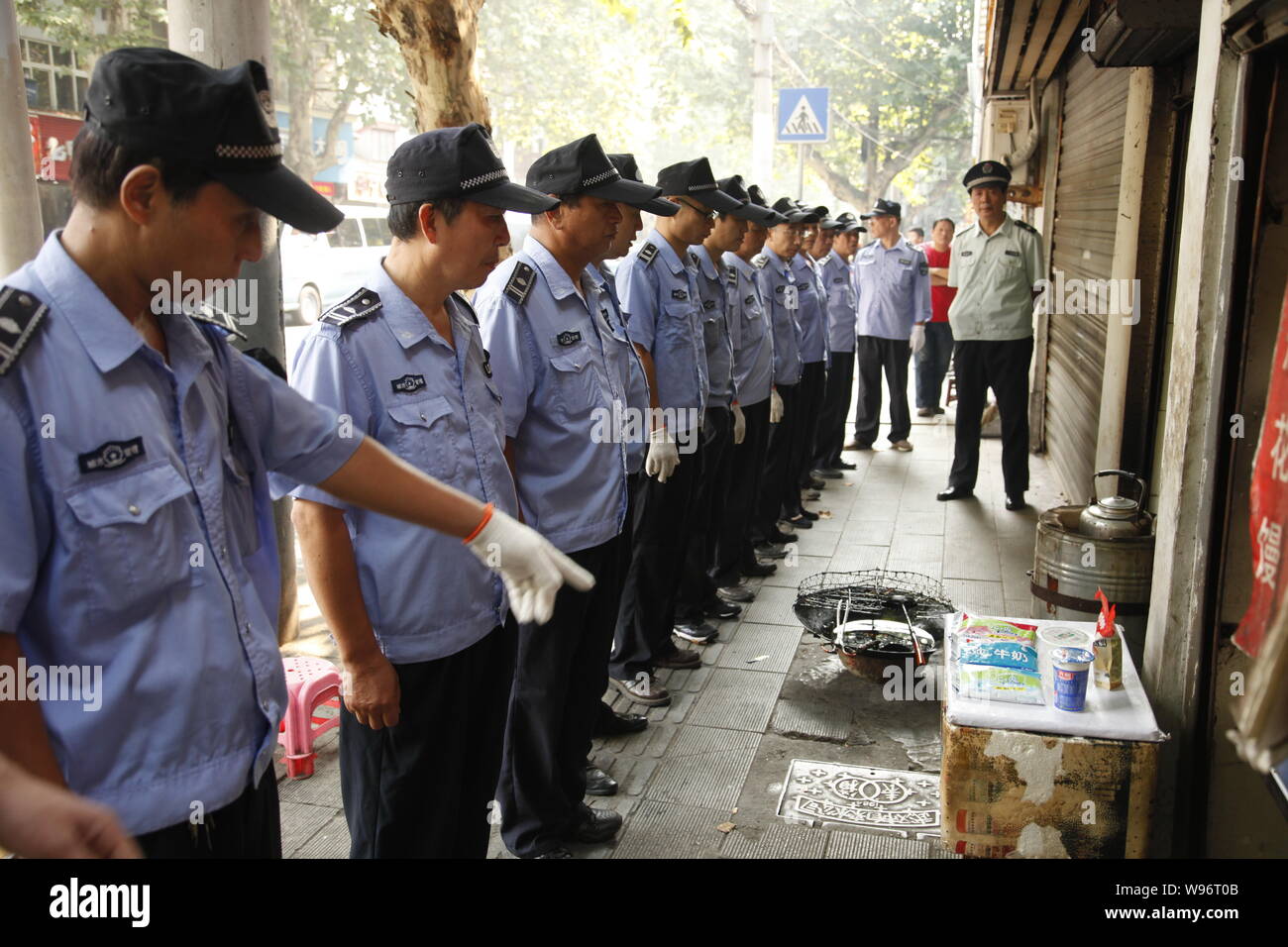 A line of urban management officers, known as chengguan, stare in ...