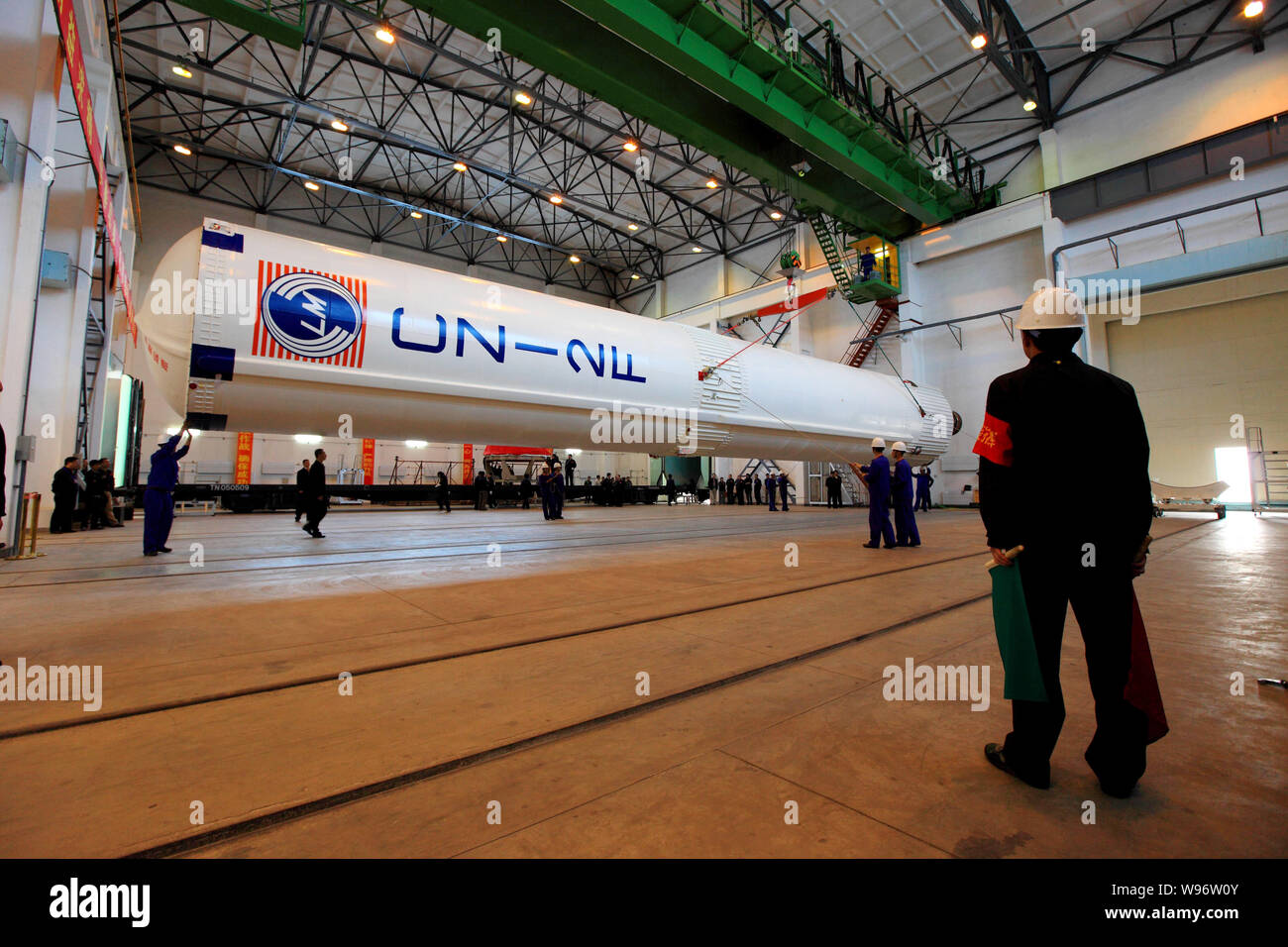 Chinese staff members hoist the first stage of a Long March 2F (CZ-2F ...
