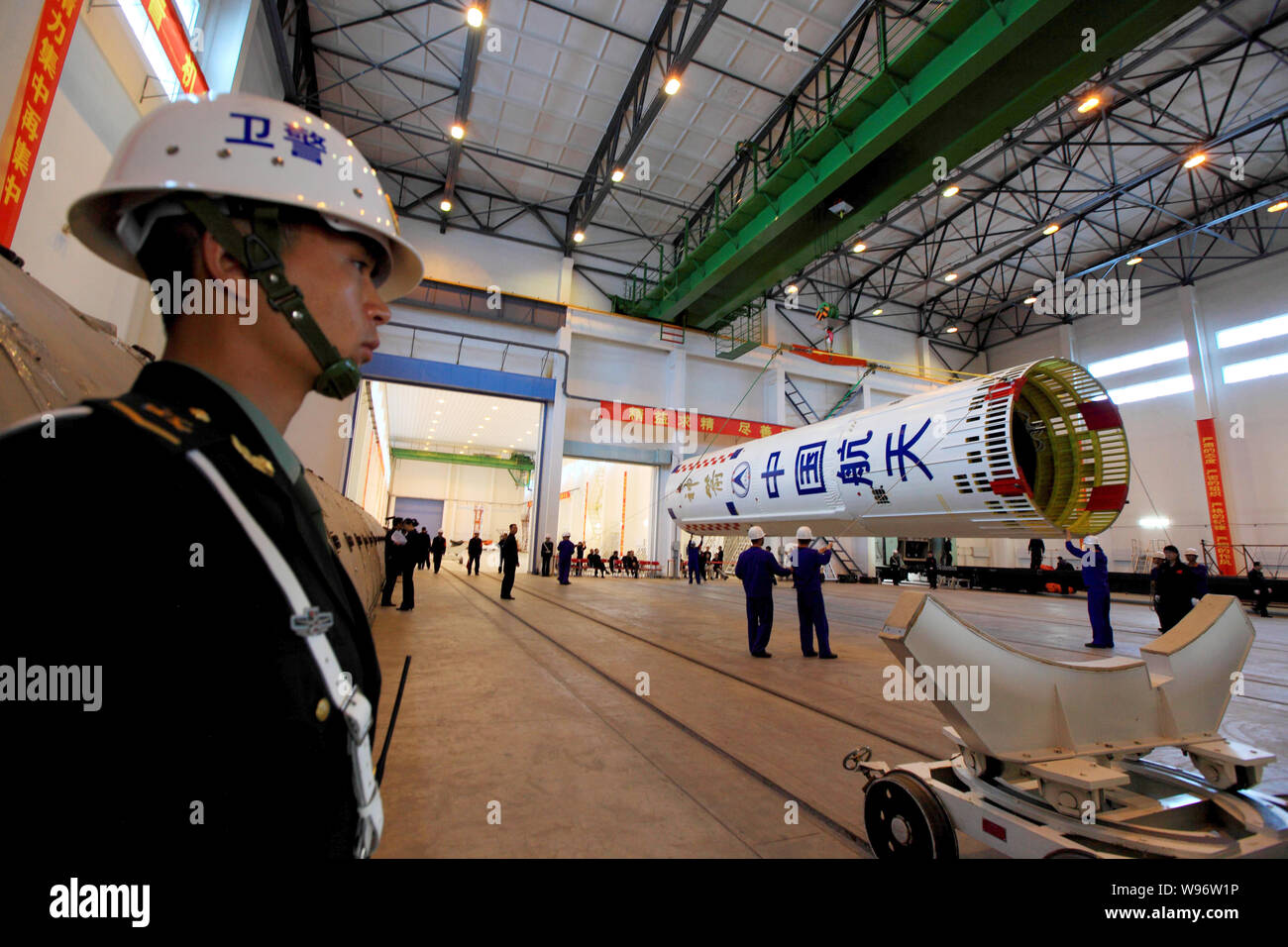 Chinese staff members hoist the second stage of a Long March 2F (CZ-2F ...
