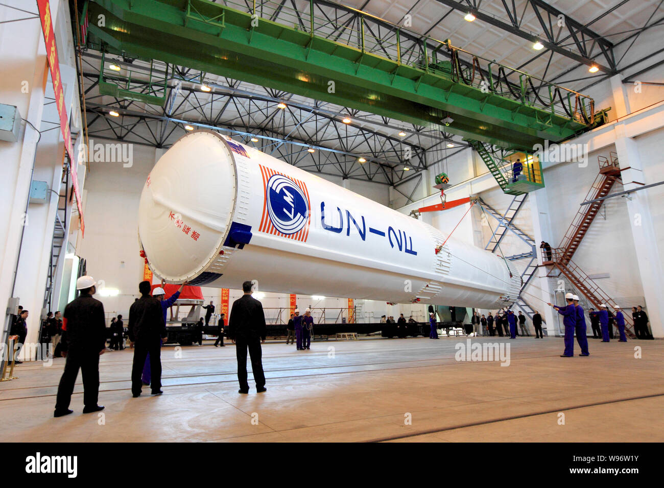 Chinese staff members hoist the first stage of a Long March 2F (CZ-2F ...