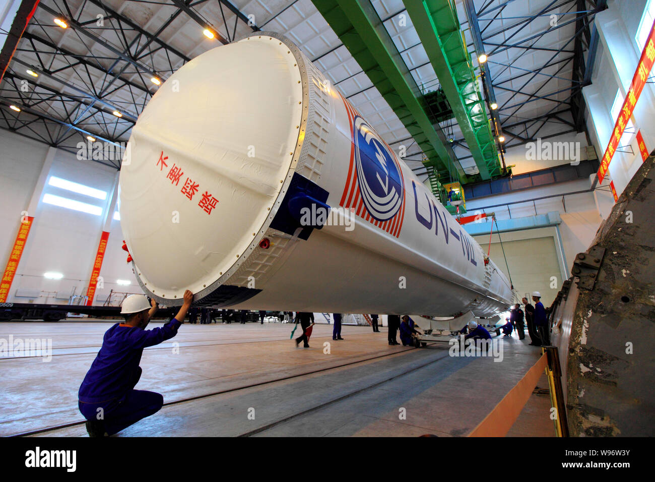 Chinese staff members hoist the first stage of a Long March 2F (CZ-2F ...