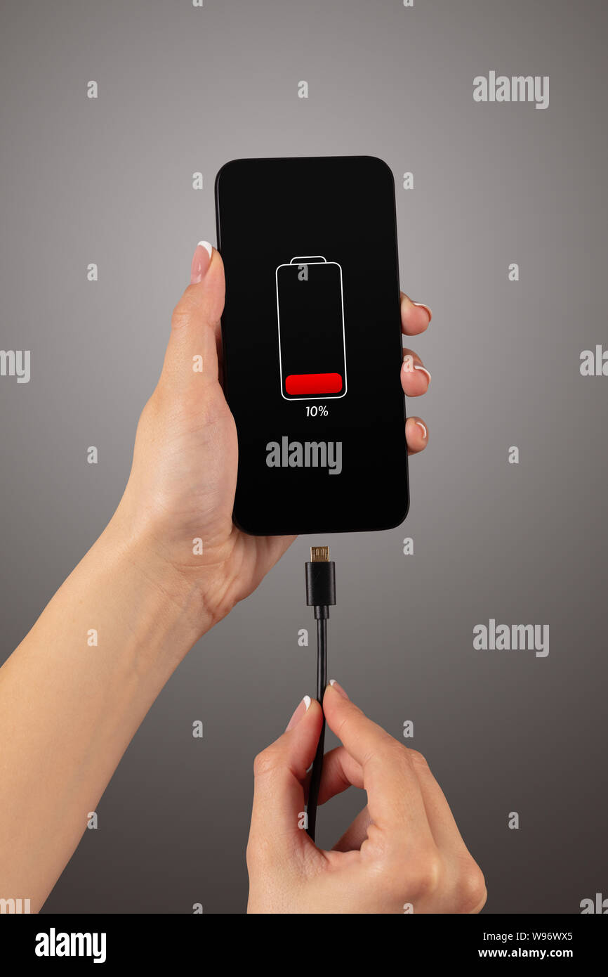 Elegant hand charging cellphone with low battery Stock Photo - Alamy