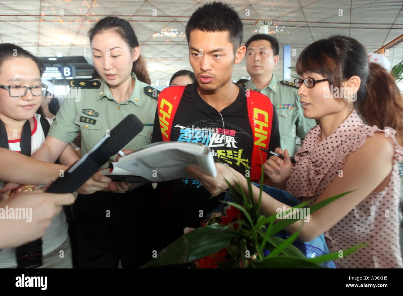Chinese Olympic badminton champion Lin Dan (black) signs for fans at ...