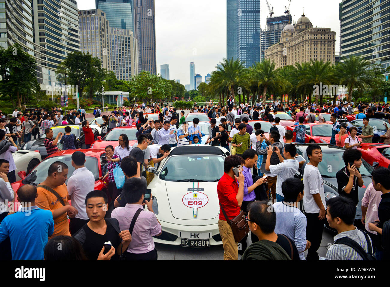 People crowd around Ferrari sports cars lined up during a parade to ...