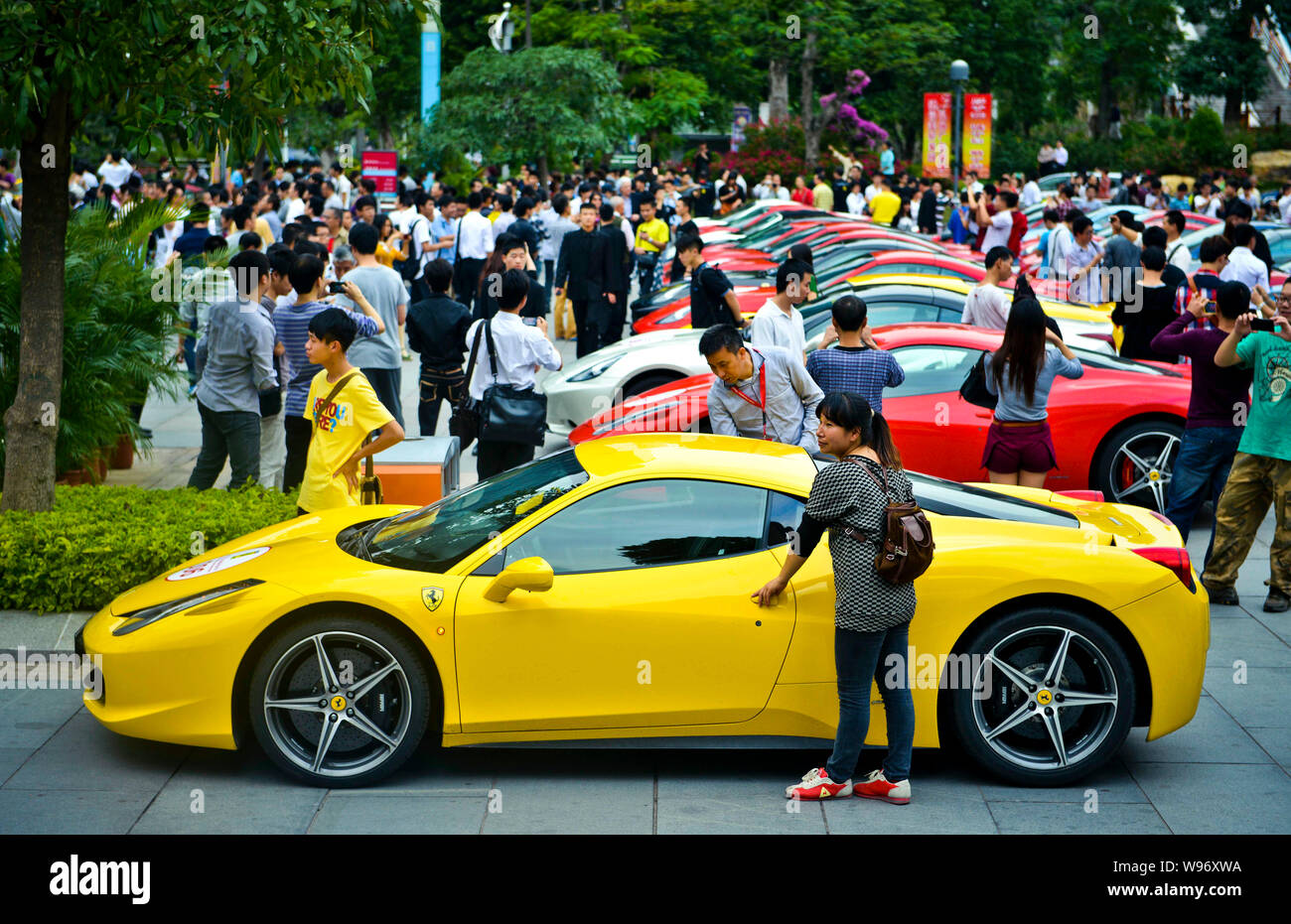 People crowd around Ferrari sports cars lined up during a parade to ...