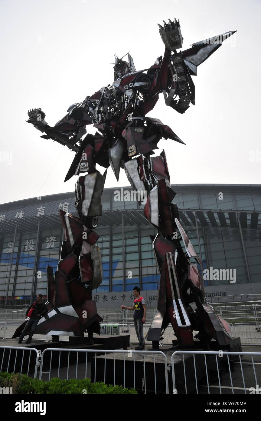 Pedestrians pose by a giant transformer model at Beijing Olympic Park ...