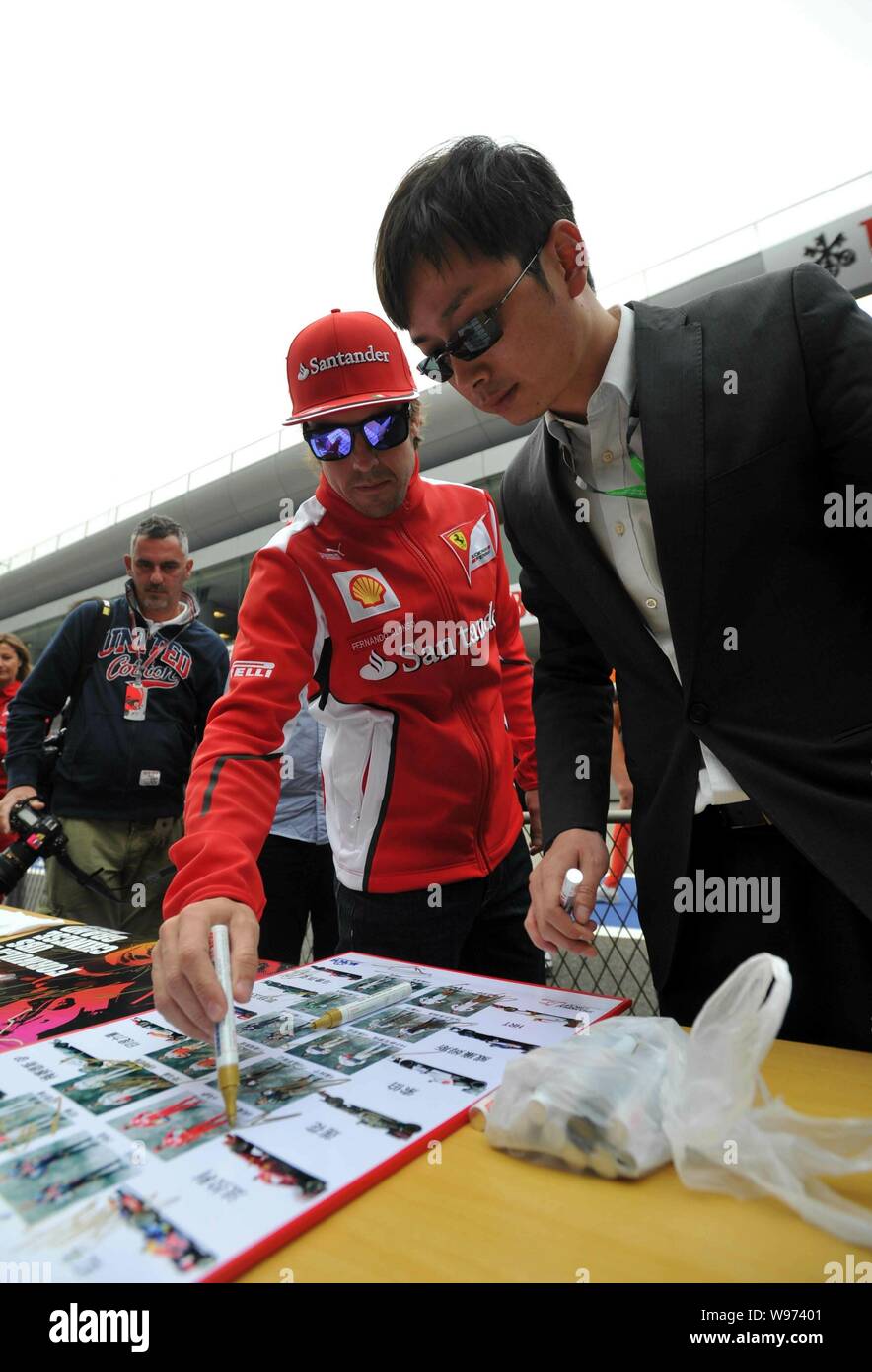 Spanish F1 driver Fernando Alonso of the Ferrari team signs for fans ...