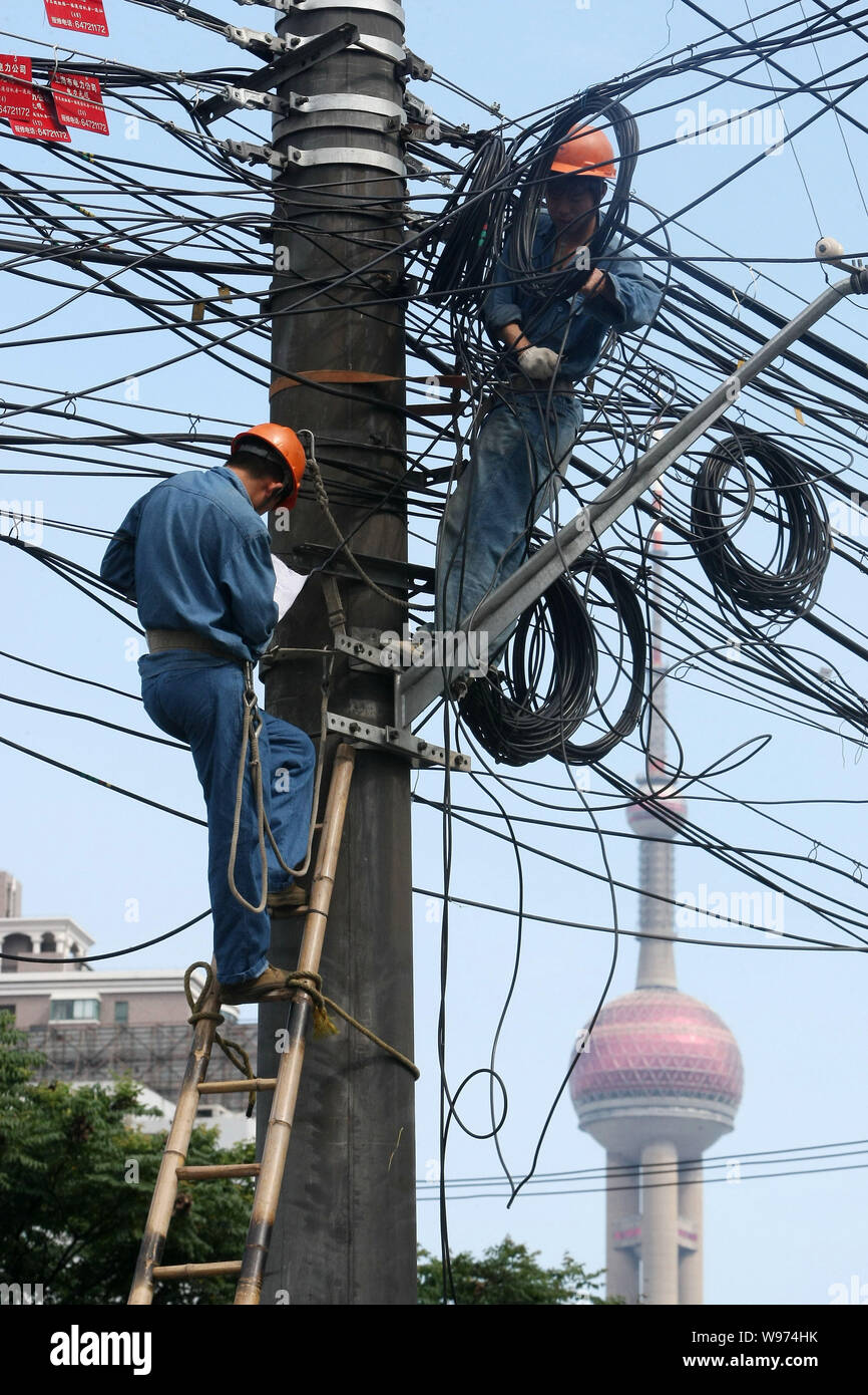 Chinese electricians check and repair electrical wires on a pole in ...