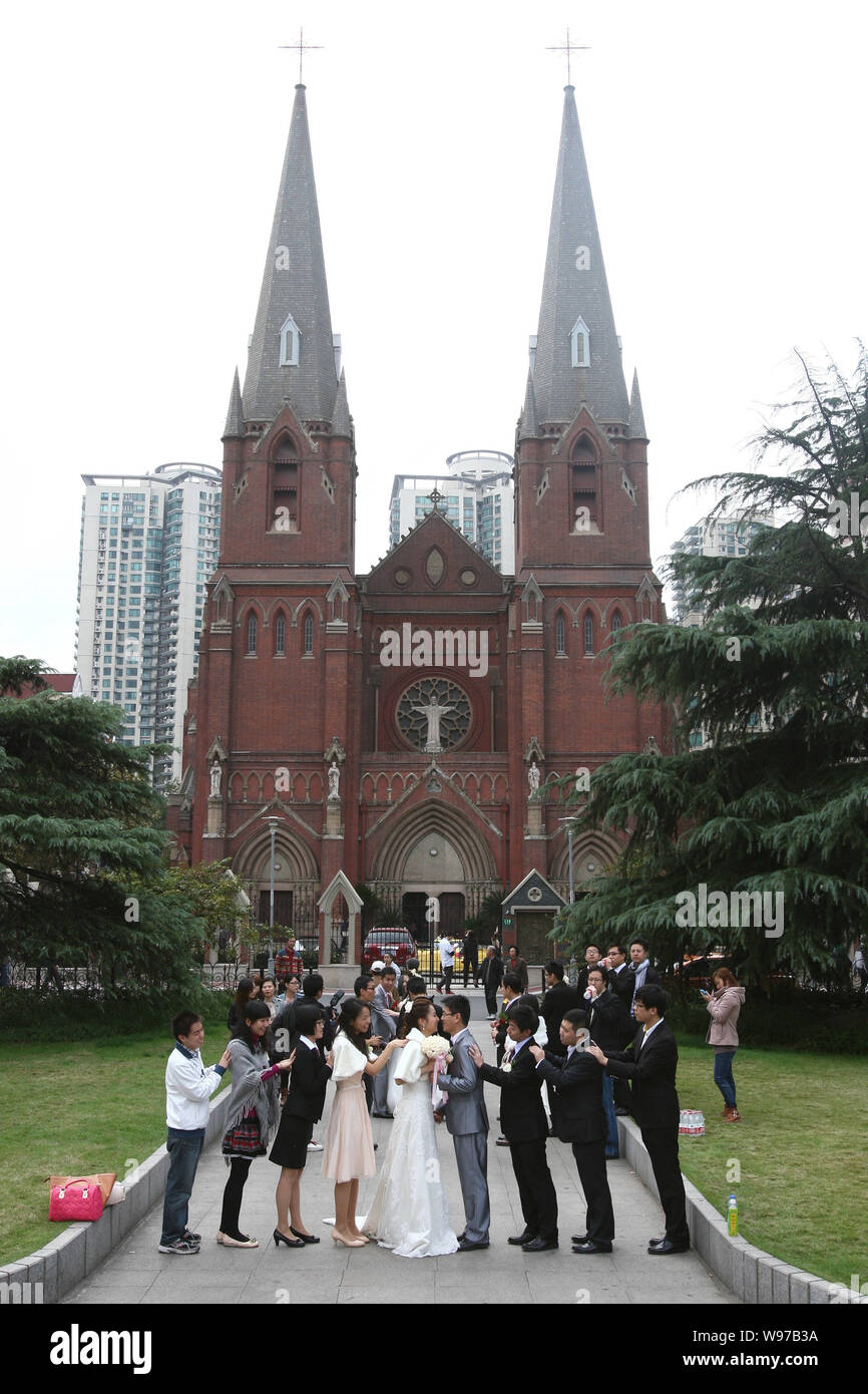 A couple of Chinese newlyweds and their friend pose for wedding photos ...
