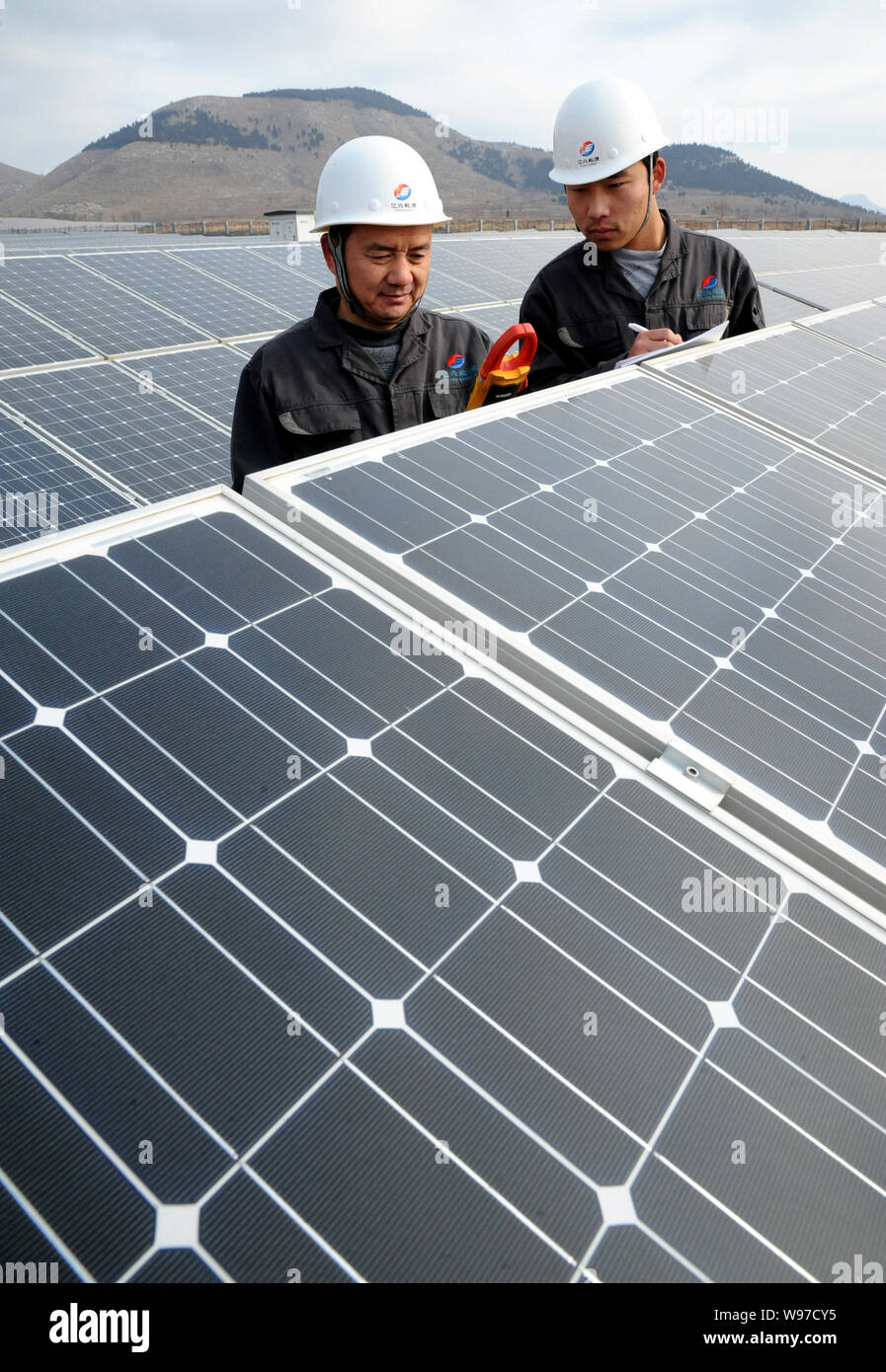 Chinese inspectors check arrays of solar panels at a photovoltaic power ...