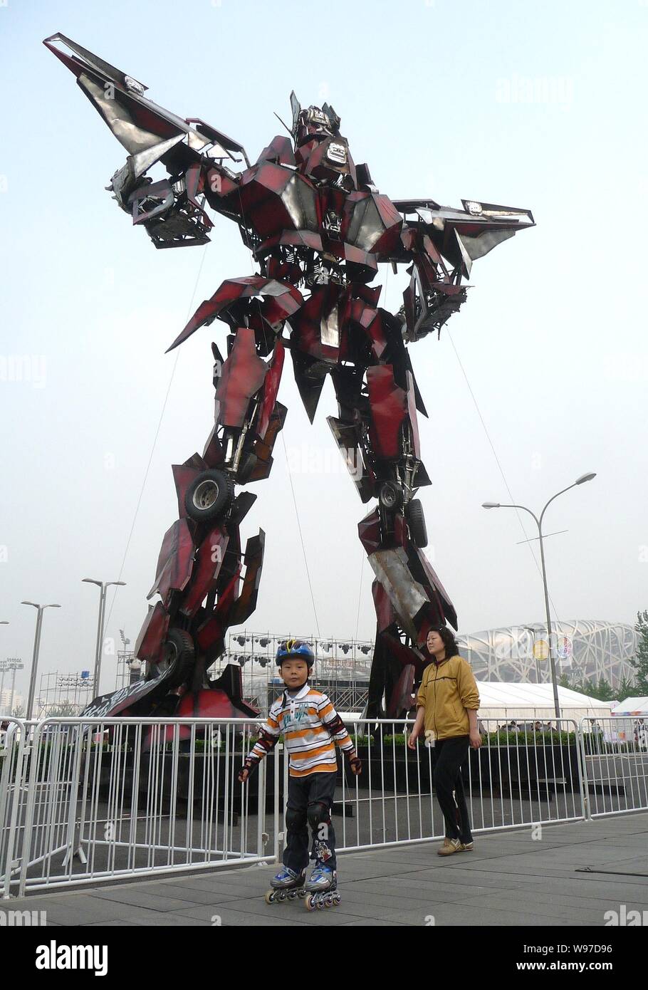 Pedestrians walk past a giant transformer model at Beijing Olympic Park ...