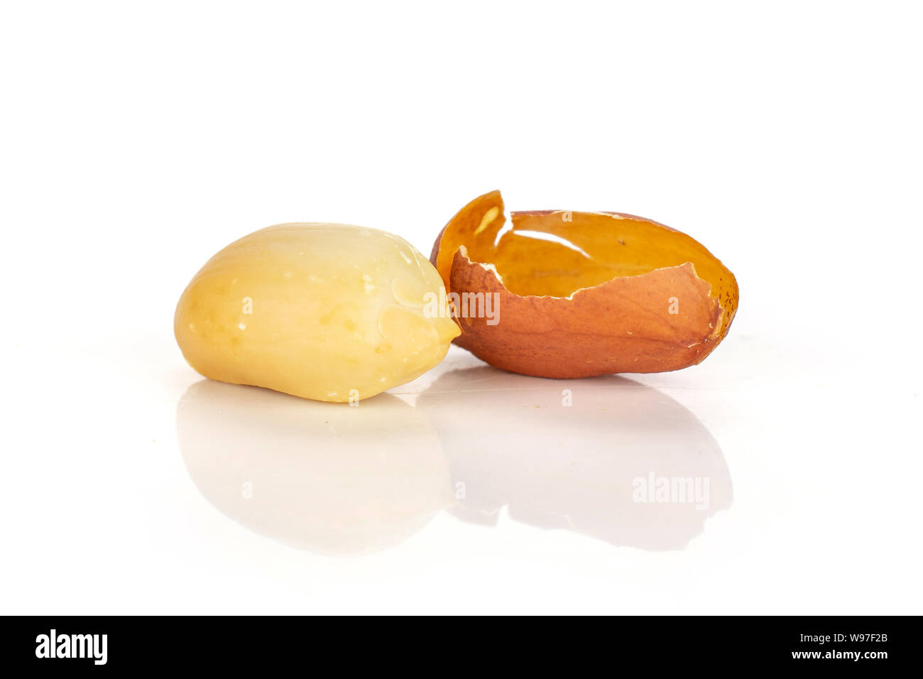 Group of two whole natural yellow peanut one with skin in closeup ...
