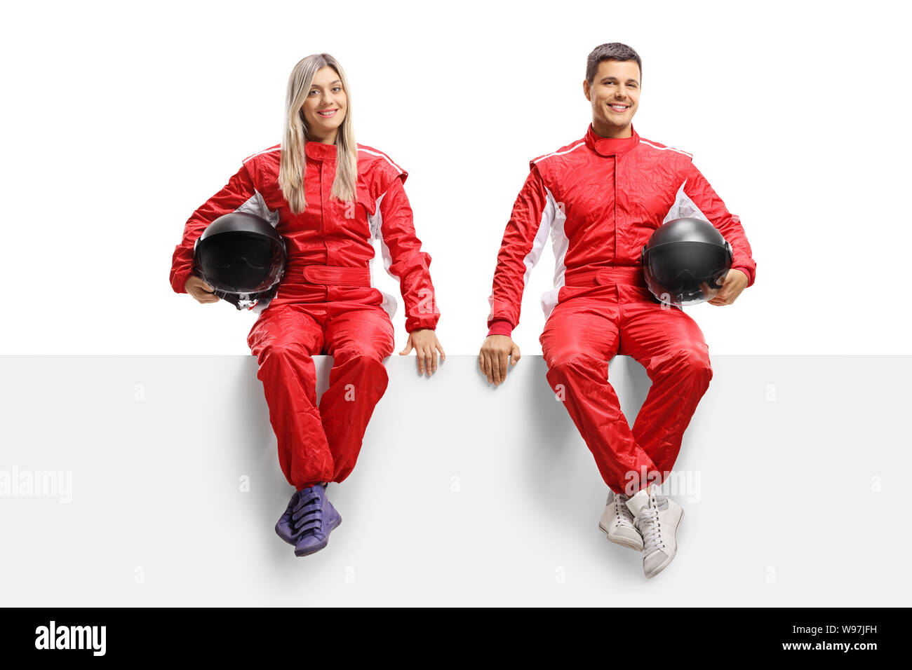 Full length portrait of a male and female car racers sitting on panel ...