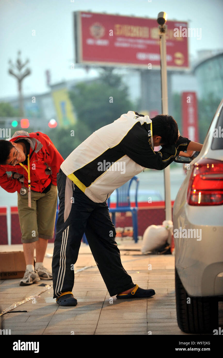 A staff member views the hand of contestant Qiu Jianjun as he competes ...
