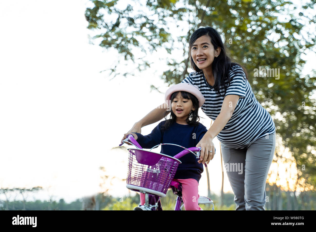 kid learning to ride bicycle with mother Stock Photo - Alamy