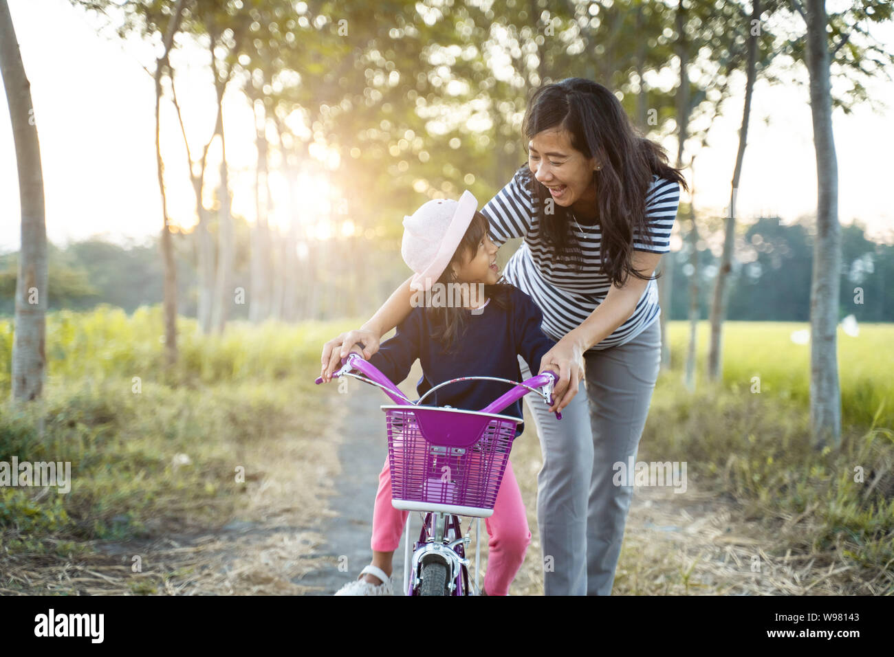 kid learning to ride bicycle with mother Stock Photo - Alamy