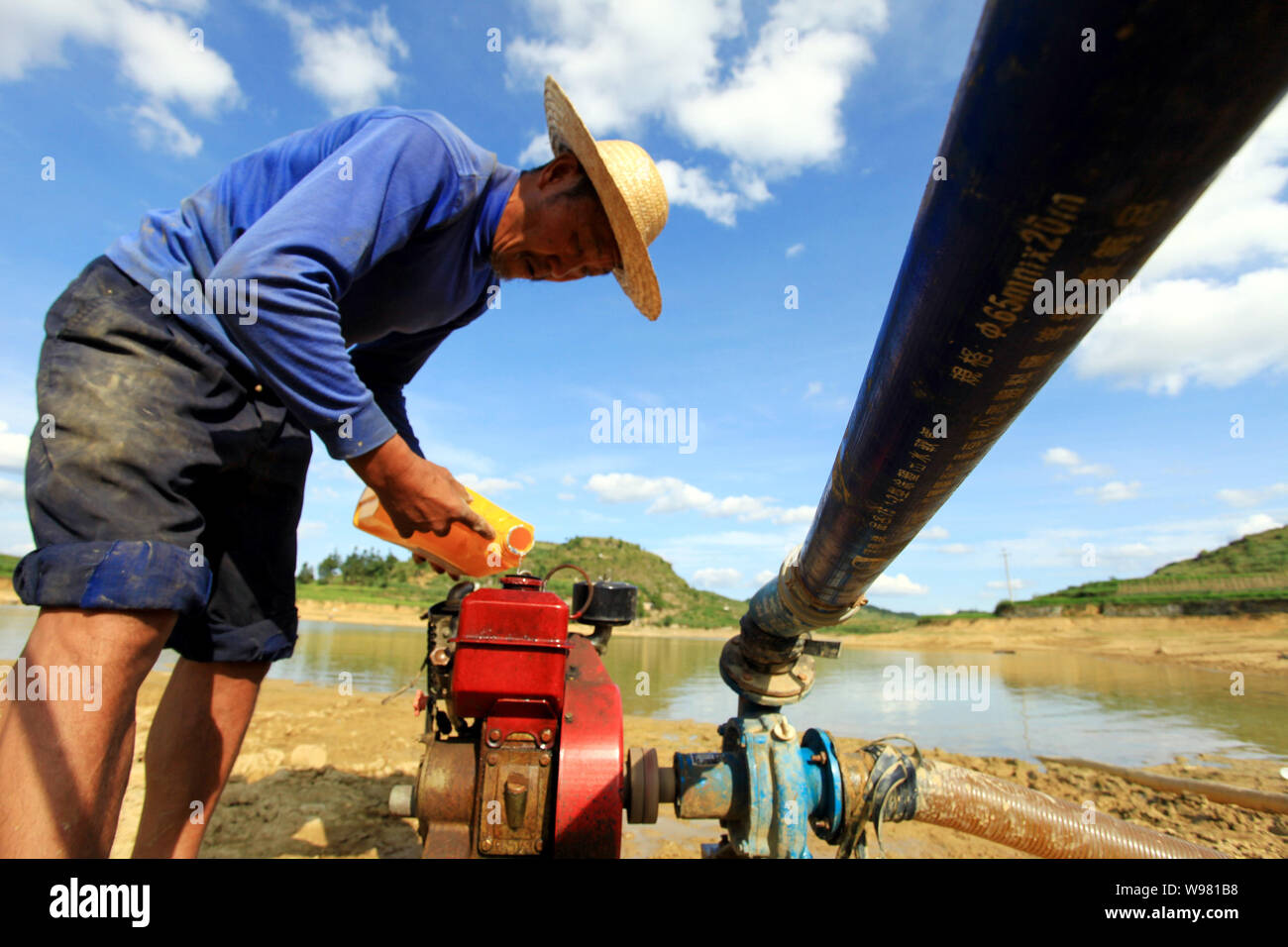 A Chinese farmer pumps water in a nearly dried-up reservoir to irrigate ...