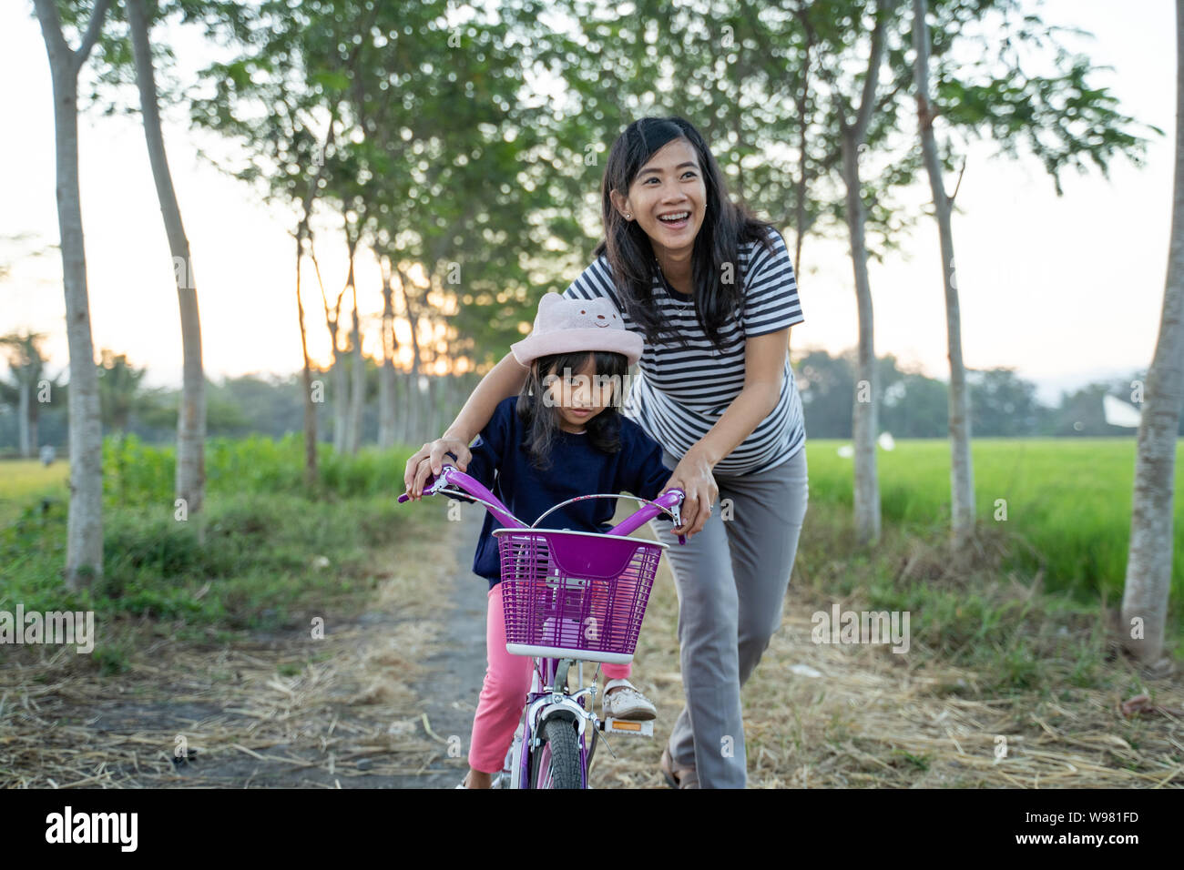 kid learning to ride bicycle with mother Stock Photo - Alamy