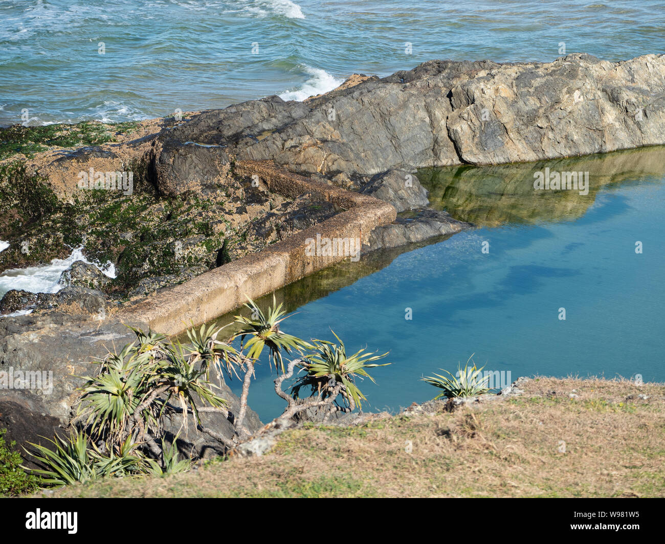 Rocks reflecting in the still clear water of a salt water rock pool fed ...