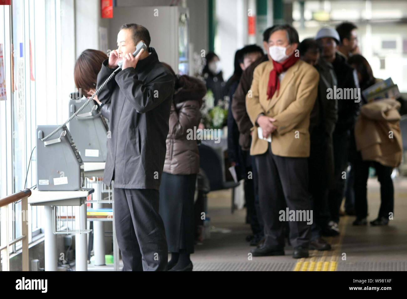 Local Japanese residents queue up to use fixed-line telephones after ...