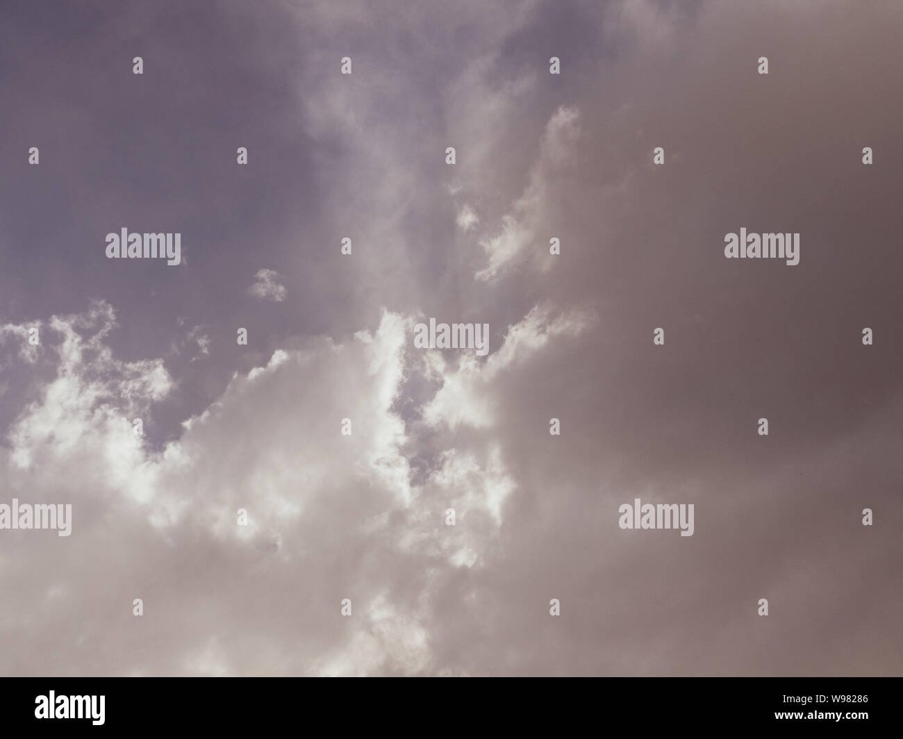 Sepia effect of clouds with sunlight shining dramatically through them ...