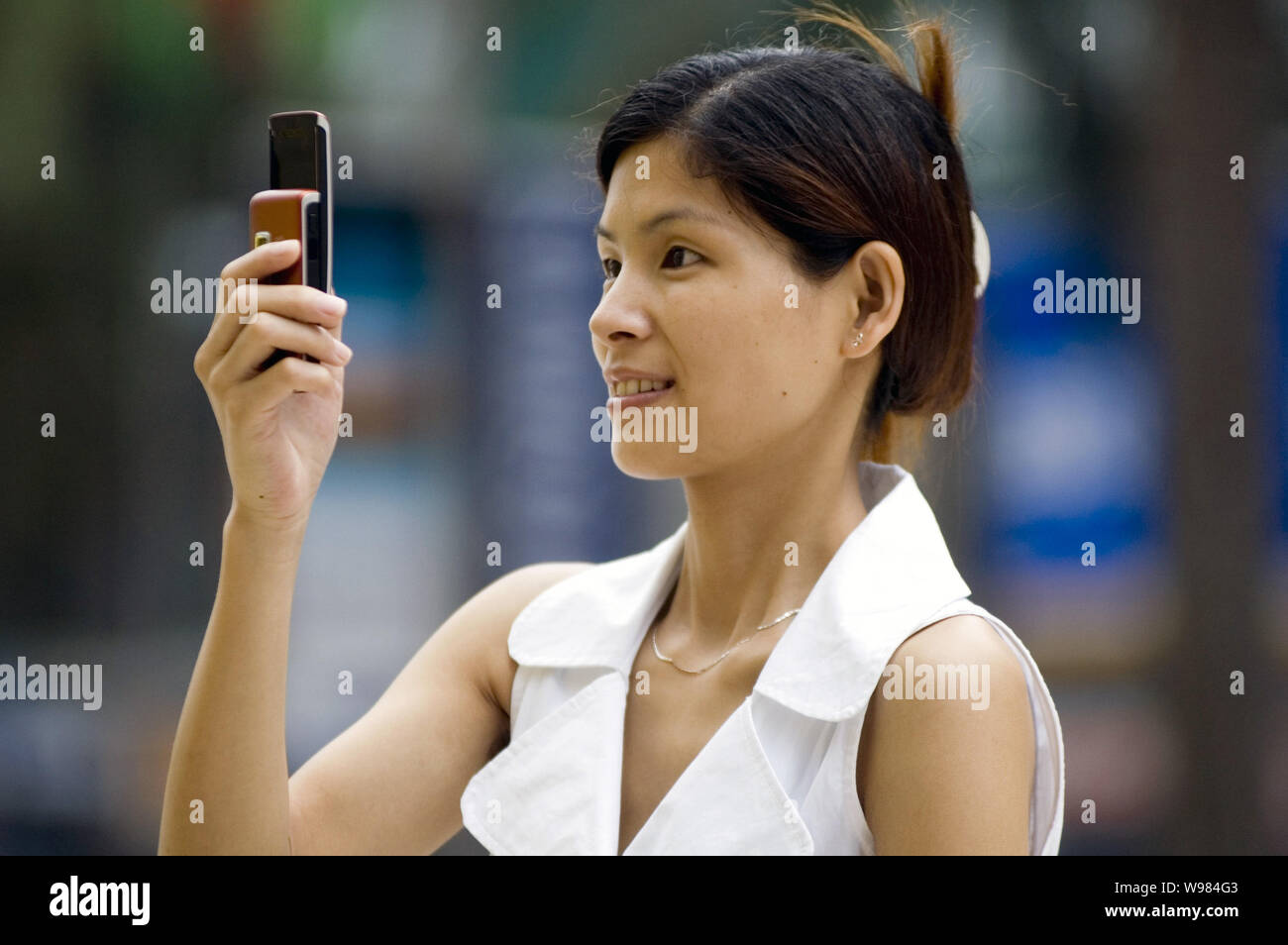 --File-- A young Chinese woman uses her mobile phone in a street in ...