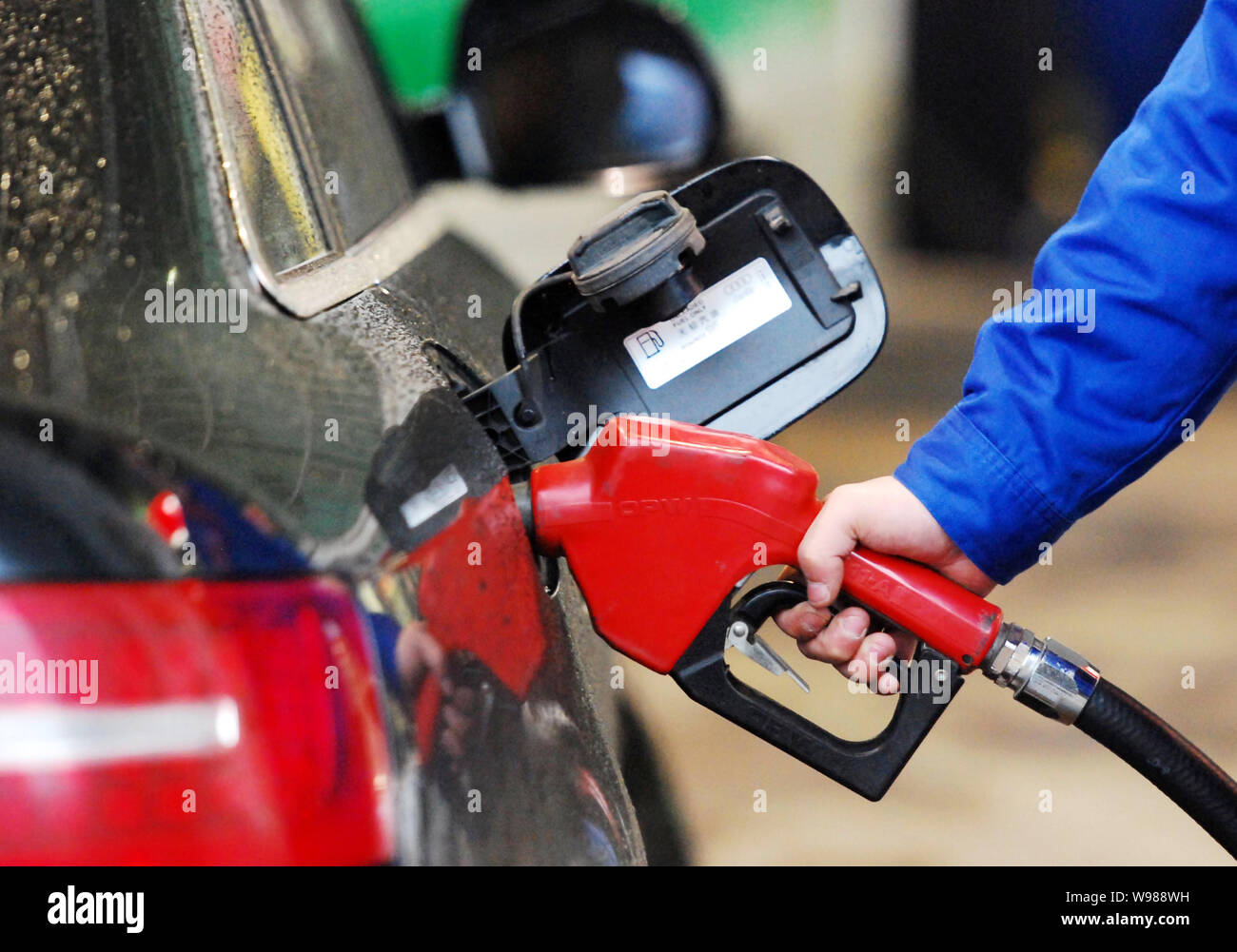 A Chinese worker refuels a car at a gas station in Jiujiang city, east ...