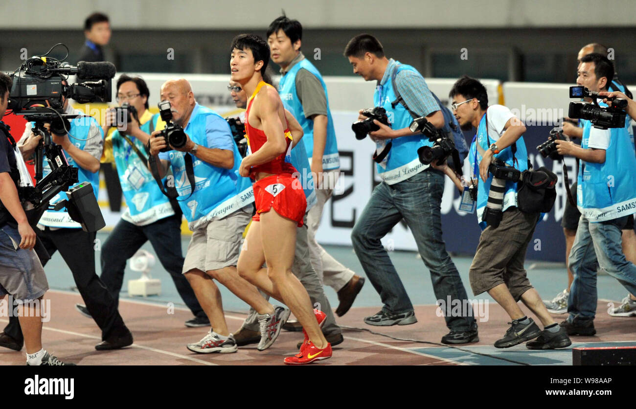 Star hurdlers Liu Xiang of China is followed by a crowd of press staff ...