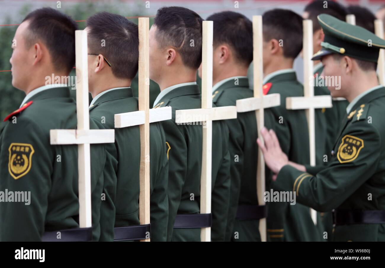 An officer of Armed Police pushes a cross on the back of another ...