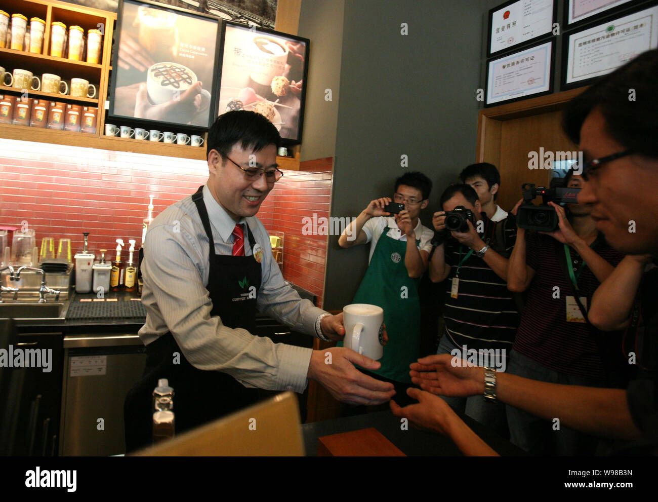 Wang Jinlong (L), chairman of the board of Starbucks Greater China, serves the first coffee to a ...